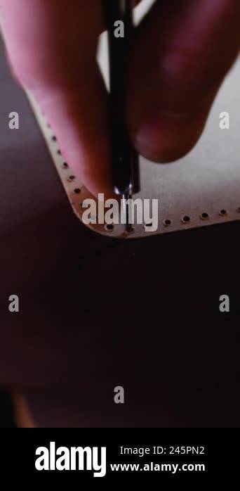 Detailed close-up of a craftsman marking leather using a perforated ...
