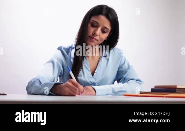 Latin business woman writing on paper, thinking, and touching her head ...