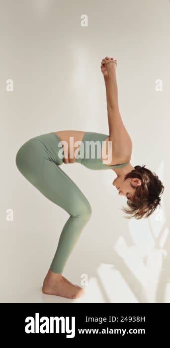Vertical shot of an athletic woman in activewear stretching her arms behind her back while ...