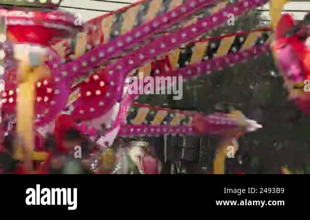 A dizzying amusement park ride spins at a fairground, creating a sense ...