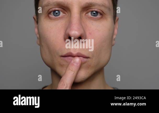 Close-up of a young man pointing to dry lips with his finger ...