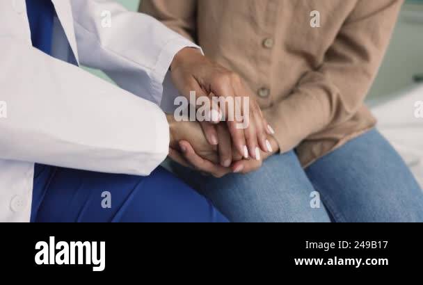Female doctor giving support to patient on consultation, touching and ...