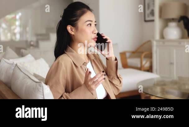 Positive cheerful young Vietnamese cellphone user talking on mobile ...