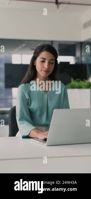 Vertical view of young Brazilian woman worker prepare report on laptop ...