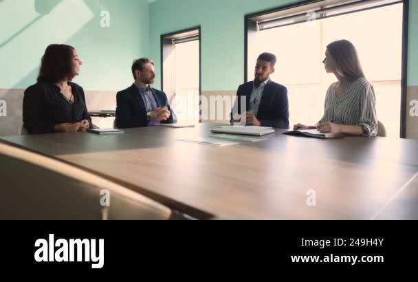 Multiethnic business partners talking at large table in office ...