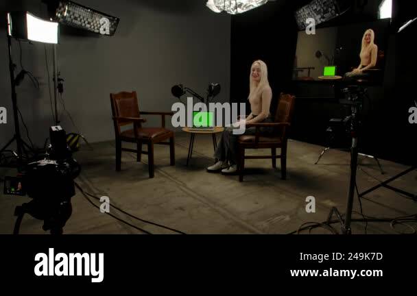 Online podcast show. Backstage shot woman guest sits in chair in podcast studio, recording ...