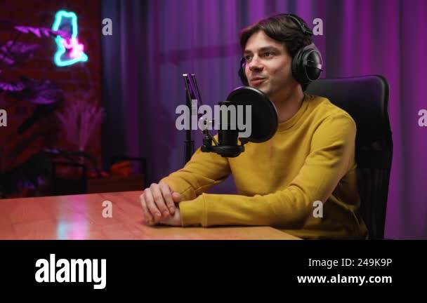 Online podcast. Man host wearing headphones, sitting at table and ...
