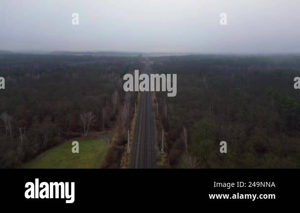 Aerial view of railroad crossing large forest under overcast sky ...