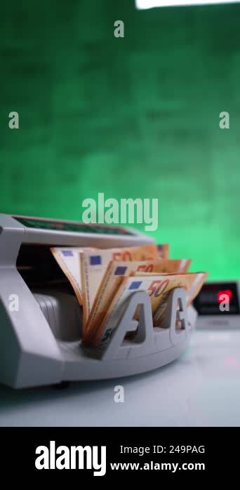 Female hand puts money into bank equipment. Fifty euro stack calculated ...