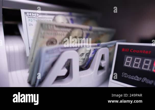 Counting one hundred dollar bills in bank equipment. Numbers change on ...
