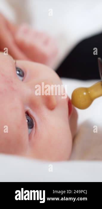 Dad's hand giving a pacifier to a newborn. Baby takes a pacifier and ...