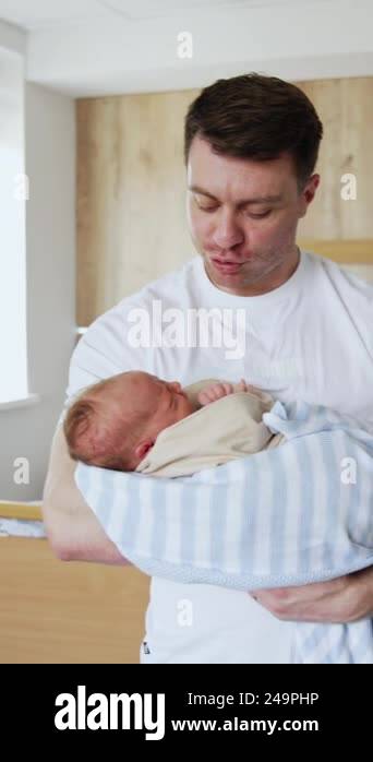 Young dad soothing and dandling newborn child. Dad takes care of his ...