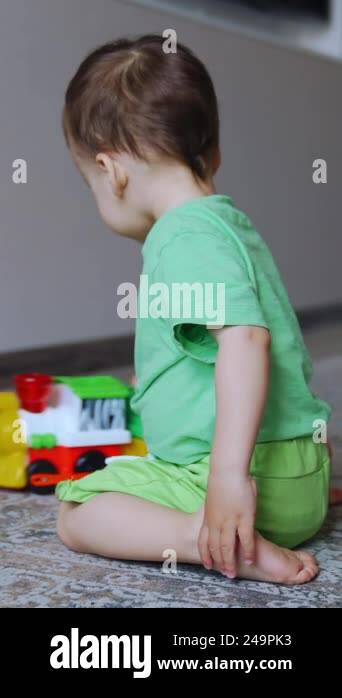 One year old toddler plays with a toy car at home. Rear view of a child ...