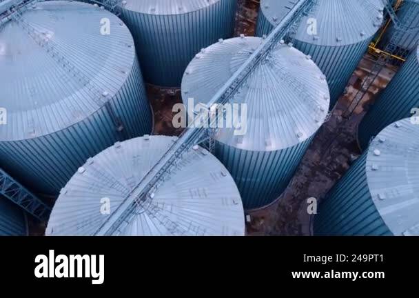 Rising over the tops of the large metal tanks for grain storage. Modern ...