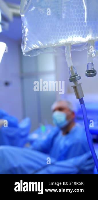 Plastic bag with saline solution hanging in surgery room. Blurred image ...