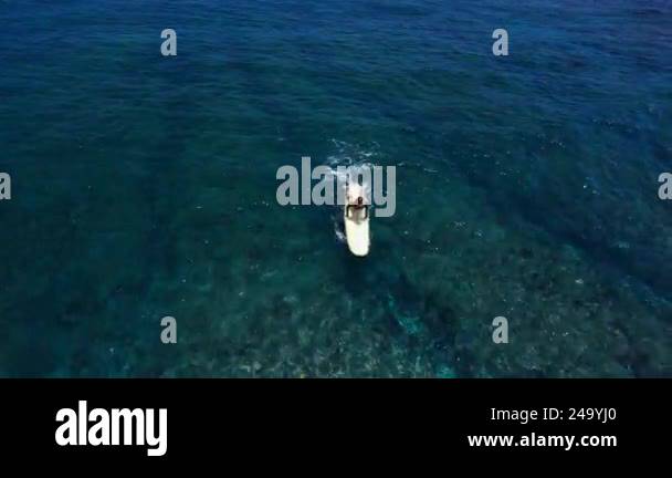 Woman on longboard in blue ocean. Drone view of woman during surfing ...