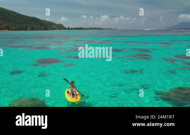 Paddling a yellow kayak in turquoise waters, a woman enjoys a sunny day ...