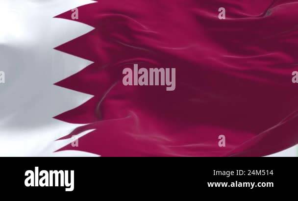Detail of the Qatar national flag fluttering. The flag is maroon with a ...
