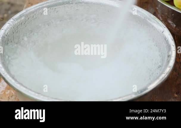 Pouring cold water into big stainless steel bowl from the water hose to ...