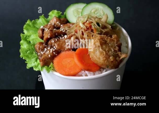 Rotating rice bowl containing teriyaki chicken with rice, vegetables ...