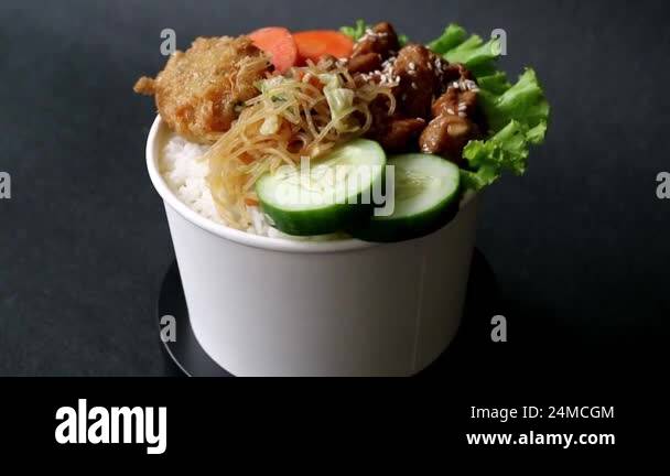 Rotating rice bowl containing teriyaki chicken with rice, vegetables ...