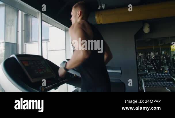 A determined man exercising on a treadmill facing large windows in a ...