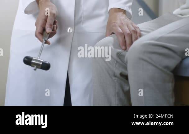 Female doctor testing patient's reactions by tapping her knee with a ...