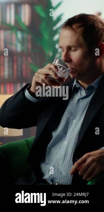 Vertical Video Old money elite gentleman drinking strong whiskey due to ...