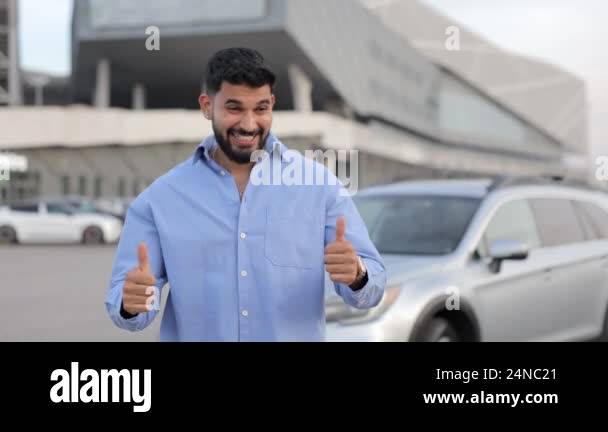 Happy confident male driver standing in front on car and looking at ...