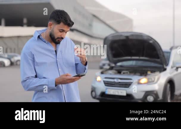 Puzzled Caucasian male driver using mobile phone, calling car repair ...