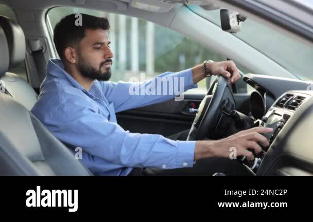 Focused male driver in casual clothes, exploring car dashboard, while ...