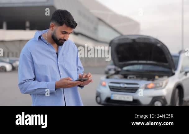 Sad guy checking time, calling car repair service, while waiting on ...