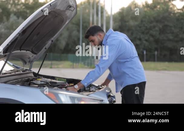Handsome Caucasian guy wearing casual inspecting broken down car on ...