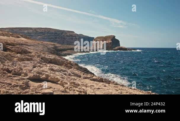 A slow-motion video of a seascape where waves crash against rocks ...