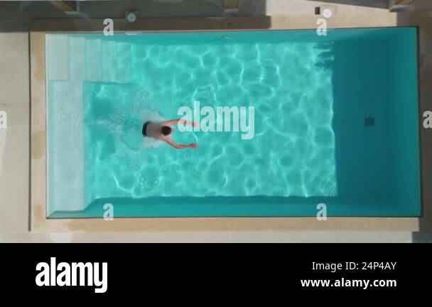 Top view man tourist doing front flip into swimming pool while relaxing ...