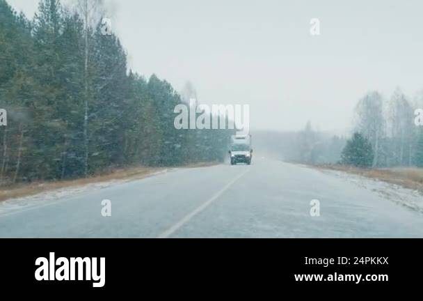 Winter road with cars. Camera moves along the asphalt road covered with ...