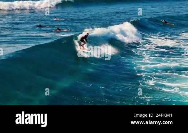 Man surfs the wave and does hand five trick by walking to the nose of ...