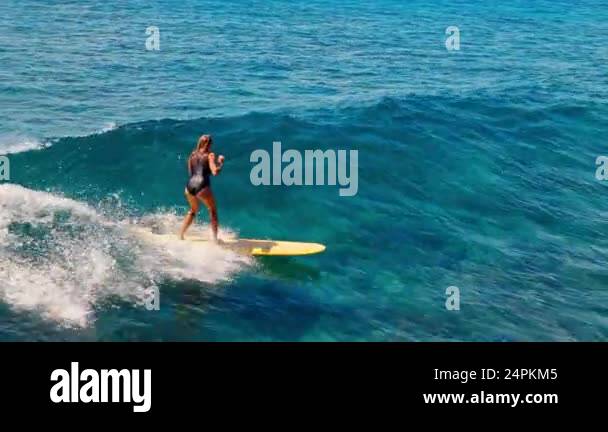 Woman surfs the wave. Aerial view of the female surfer riding the wave ...