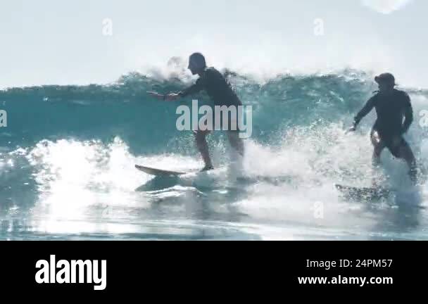HIMMAFUSHI, MALDIVES - OCTOBER 28, 2024: Two male surfers rides the ...
