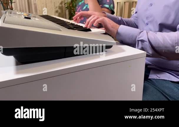 A young music teacher guides a child in learning to play the digital ...