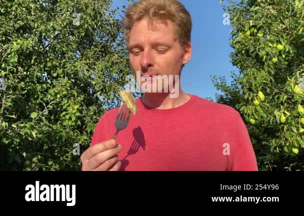 A young man enjoys a casual lunch outdoors in a lush green park ...