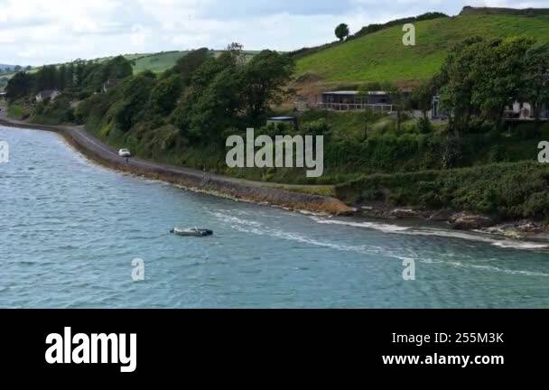 A calm river flows beside a winding road surrounded by trees and hills ...