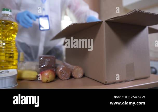 Social service volunteer Caucasian man puts food donation in a box for ...