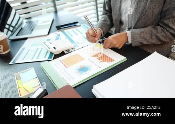 Young Asian accountant doing paperwork using laptop computer sitting in ...