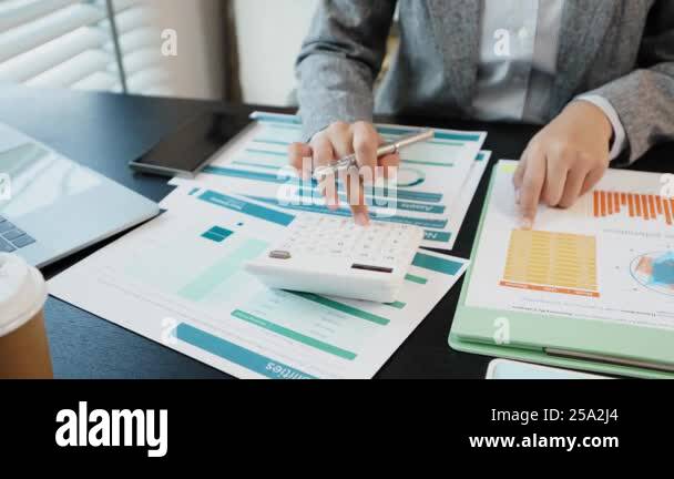 Young Asian accountant doing paperwork using laptop computer sitting in ...