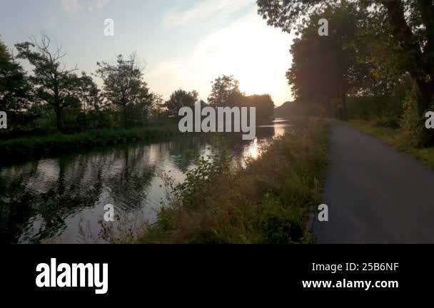 A peaceful and serene canal pathway at sunset, beautifully reflecting ...