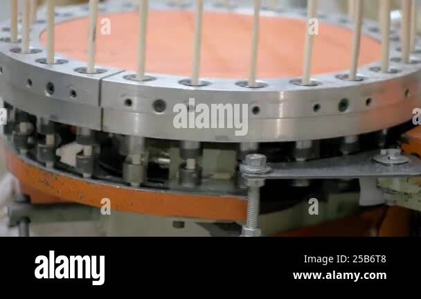 A machine processes wooden dowels, arranging them vertically in a ...