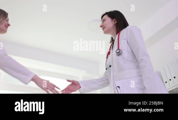 Professional physician extends hand to greet colleague. Smiling doctors ...