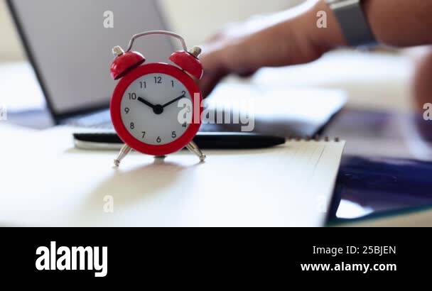 A red alarm clock and modern laptop emphasize the importance of time ...