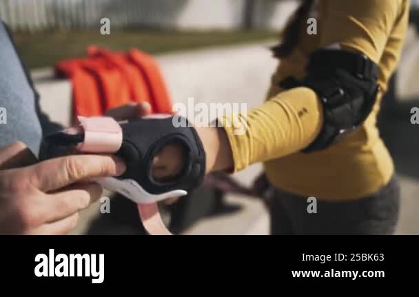 Close-up of adult hands assisting a child in securing protective gear ...